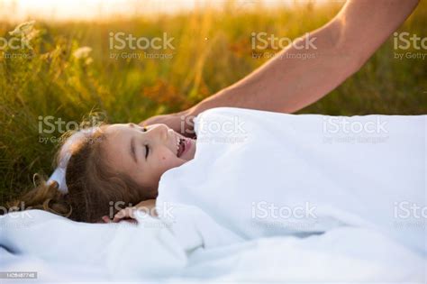 소녀는 풀밭의 하얀 침대에서 자고 신선한 공기를 마신다 아빠의 손이 부드럽게 머리를 두드린다 보살핌 보호 국제 어린이날 모기에