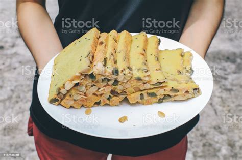 손으로 들고 흰색 접시 수 제 높은 섬유 자연 건강 식품 슬라이스 호밀 빵 도마에 녹색 배경의 씨앗이있는 통곡물 호밀 빵 갈색에