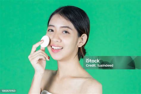 예쁜 아름다움 젊은 아시아 여자 녹색 고립 된 배경 위에 면 패드와 그녀의 얼굴을 청소 건강한 피부와 화장품 컨셉 건강관리와
