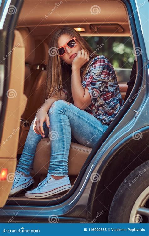 Portrait Of A Beautiful Girl In A Fleece Shirt And Jeans Sitting In
