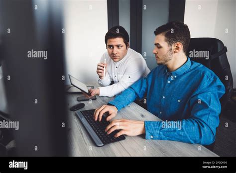 Two Young Caucasian Programmers Working On Desktop Computers In The