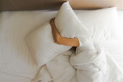 위로 깨어 후 침대에서 스트레칭 여자 다시 보기 여자는 아침에 일출과 깨어 후 침대에 스트레칭 하면서 큰 흰색 창 근처에 앉아 다시 보기 건강한 생활방식에 대한 스톡 사진