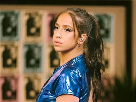 A Woman With Long Hair Wearing A Shiny Blue Top And Ear Piercings