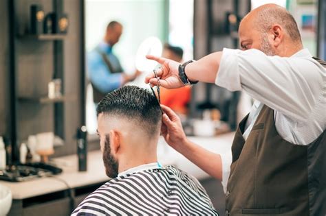 Peluquero cortando cabello en barbería Foto Premium