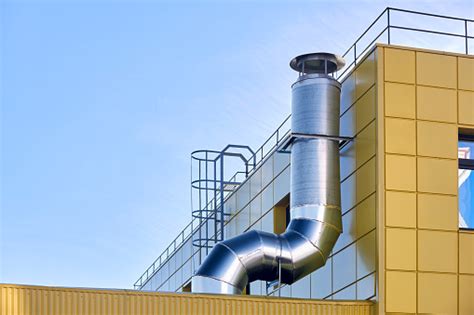 알루미늄 복합 패널 노란색과 파란색 상업용 건물 외관 스테인레스 스틸 굴뚝 파이프 덕트 파이프 라인 맑은 푸른 하늘 아래 계단이있는 산업용 보일러 실의 파이프 라인 관로에