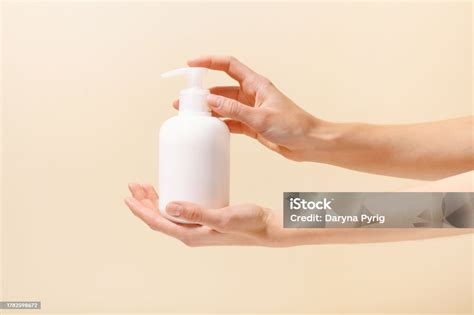 여성의 손은 베이지 색 고립 된 배경에 몸과 얼굴 크림 모형의 흰색 항아리를 들고 있습니다 미용 제품의 개념 스킨 케어 손에