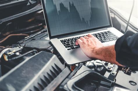 Premium Photo | Cropped hand of mechanic using laptop while repairing car engine