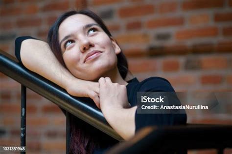 벽돌은 난 간 동 자에 그녀의 머리와 함께 건물의 계단에 서 있는 검은 드레스 입은 혼합 인종의 젊은 아름 다운 모델의 실내 초상화 검은색에 대한 스톡 사진 및 기타 이미지