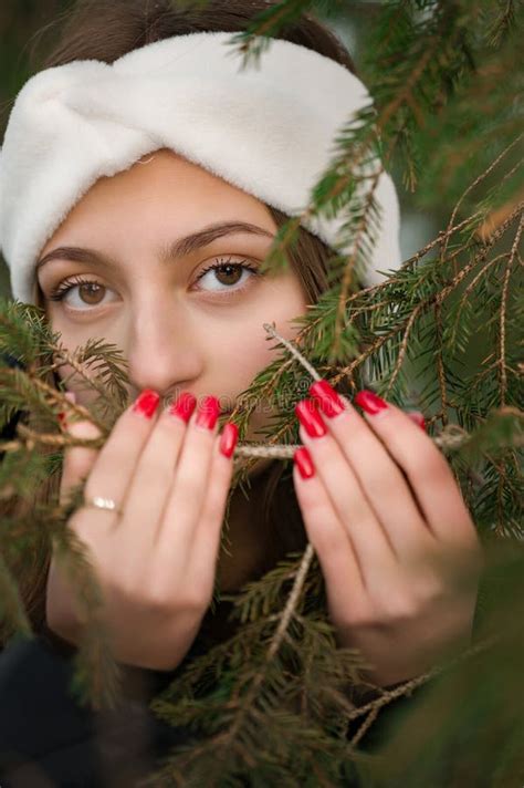 Winter Portrait Of A Girl Looking Through The Branches Of A Spruce