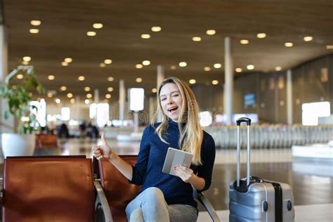 Female Person Sitting In Waiting Room With Valise Using Tablet And