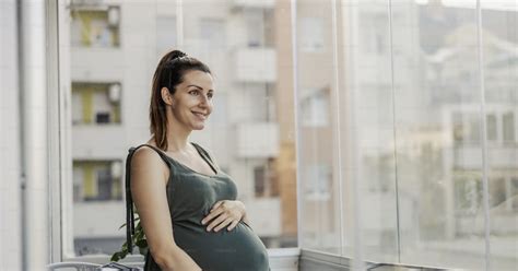 축복받은 임신과 가사일 임산부는 테라스에 서서 배를 잡고 회전식 건조기에서 말리는 아기 옷을 봅니다 아내와 집안일 사진 Unsplash의 포니 테일 이미지