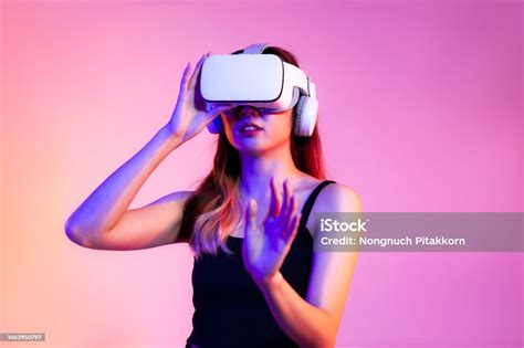 메타버스 컨셉 블랙 탱크 탑에 흰색 Vr 헤드셋 손을 대고 핑크색 스크린 배경에서 보고 놀고 있는 젊은 아시아 여성 T 가상현실