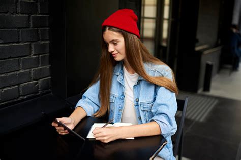 집중된 매력적인 젊은 여성 유학생 교육 응용 프로그램을 사용 하 여 Wifi에 연결 하는 현대적인 터치 패드에 카피북에서 훈련을