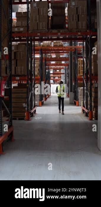 Warehouse Worker Wearing A Safety Vest And Hardhat Walks Through