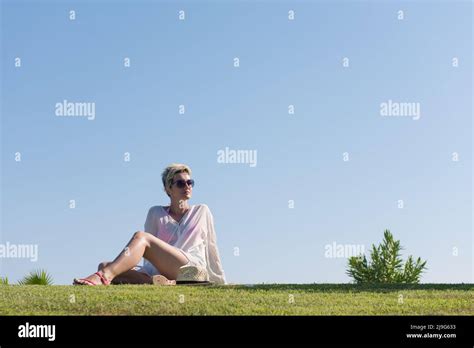 Woman Lying And Reading Her Favorite Book On A Meadow Covered With
