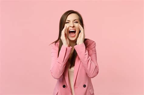 카메라를 보고 재킷에 미친 젊은 여자의 초상화 파스텔 핑크 벽 배경에 고립 된 입 근처 손 제스처로 비명 사람들은 진심으로 감정