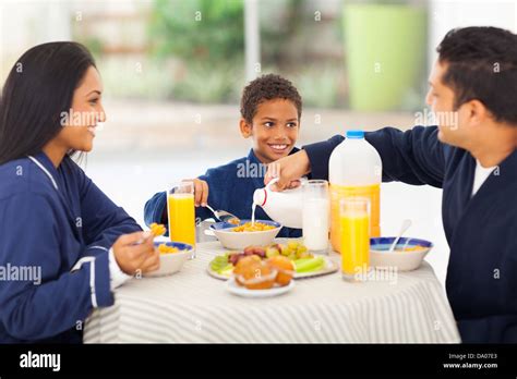 loving father pouring milk in his son's corn flakes during breakfast ...