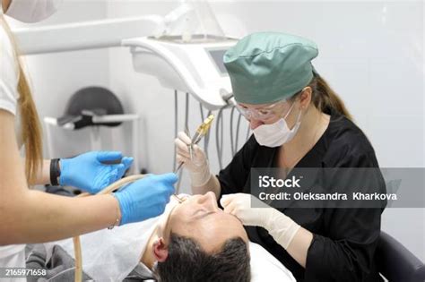 치과 의사 클로즈업 여성 환자 치과 진료실에서 충치 치료 간호사 의사의 손 치아 청소 치료 및 근관 충전을 만드는 치과 의사 보조 중성화 입 건강 진단에 대한 스톡 사진 및