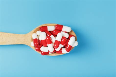 Cápsulas de pastillas rojas y blancas sobre un fondo azul Foto Premium