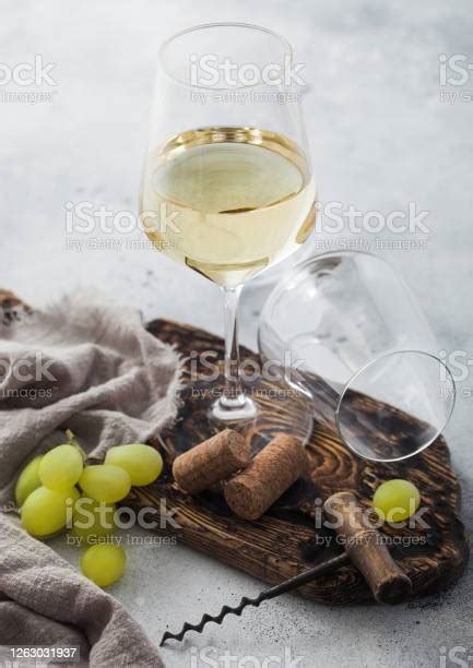 밝은 배경에 린넨 천이있는 나무 판에 코르크 코르크 나사 및 포도가있는 흰색 수제 와인 한 잔 0명에 대한 스톡 사진 및 기타