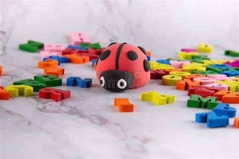 Nice Small Ladybug Made Of Light Modelling Clay Staying On White Marble Table Among Different