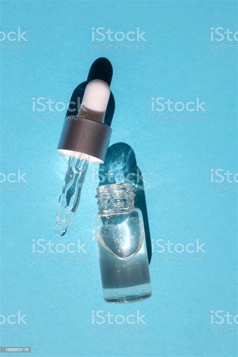 파란색 배경에 화장품 액체가있는 유리 점적기 병은 그림자를 드리운다 상단보기 수직 이미지 0명에 대한 스톡 사진 및 기타 이미지