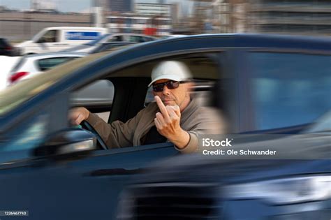 부주의 한 남성 드라이버 선글라스와 모자 몸짓 그의 가운데 손가락 운전 하는 동안 부정적인 태도와 도로 분노에 대 한 음란 한 기호 씨발 당신 손 제스처 차에 대한 스톡