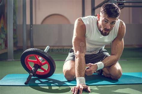 Muscular Man Taking Break After Training With Ab Wheel In Gym Stock