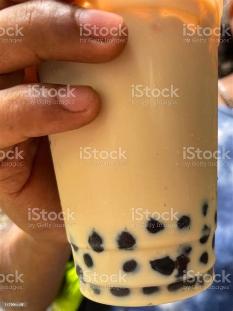 알아볼 수 없는 사람이 들고 있는 플라스틱 컵에 빨대가 있는 버블티 음료의 전체 프레임 이미지는 전경에 초점을 맞춥니다 각얼음에