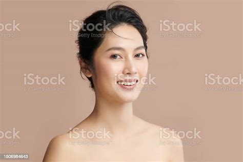 베이지 색 배경에 깨끗한 신선한 피부를 가진 아름다운 젊은 아시아 여성 얼굴 관리 얼굴 치료 화장품 아름다움과 스파 아시아 여성