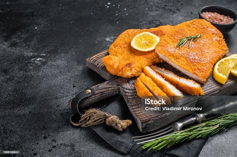 허브가 있는 나무 판에 얇게 썬 와이너 슈니첼을 튀긴다 검은 색 배경 맨 위 보기입니다 복사 공간 비엔나 슈니첼에 대한 스톡