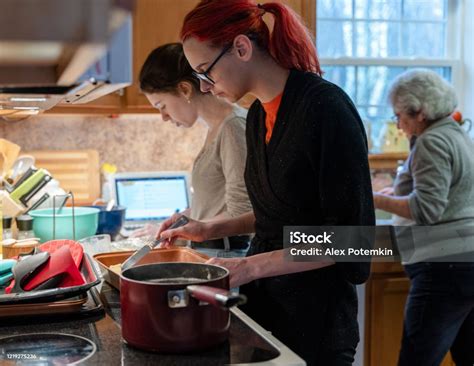 바쁜 부엌에서 가족 요리 그녀의 할머니와 여동생이 모두 백그라운드에서 요리하는 동안 십대 소녀는 파이팬을 기름칠 16 17 살에 대한 스톡 사진 및 기타 이미지 Istock