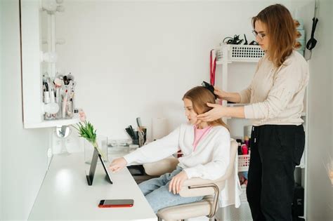 Premium Photo Mom Does Her Daughter Hair A Teenager Uses A Tablet