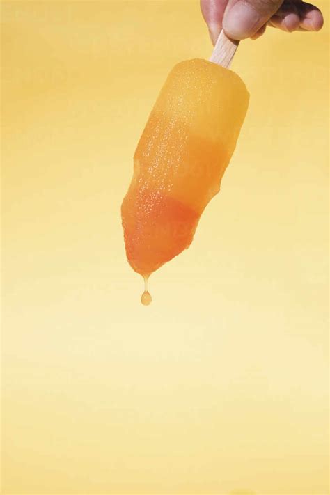 Cropped Hand Of Mid Adult Woman Holding Dripping Popsicle Against