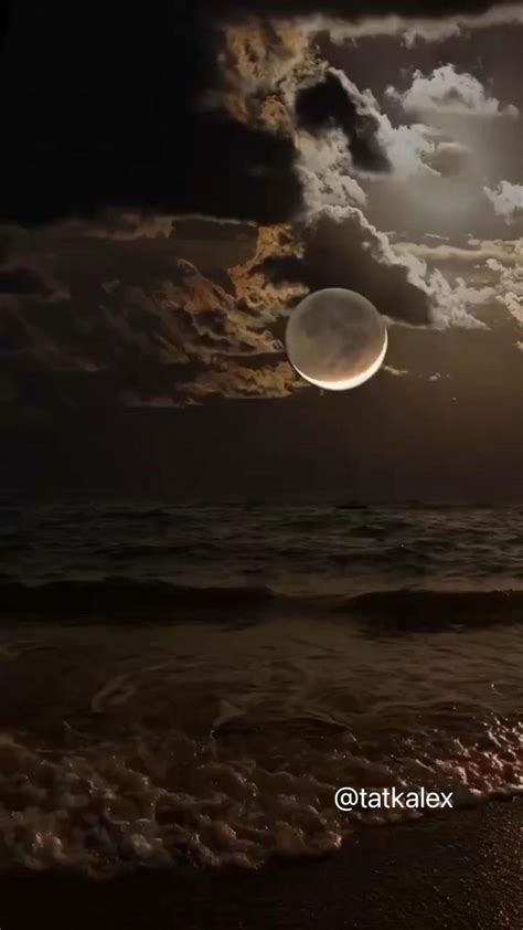 the moon over the water at night with clouds and waves