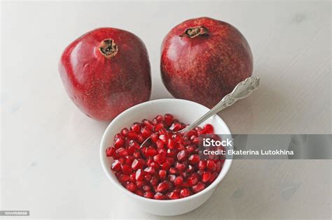 붉은 익은 석류 알갱이 숟가락으로 흰 그릇에 거짓말 큰 익은 빨간 Granets 또는 가닛입니다 흰색 바탕에 빨간색 잘 익은