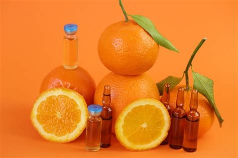 바이러스에 대한 면역의 비타민 C 예방 밝은 오렌지 배경에 앰플과 신선한 오렌지와 만다린의 비타민 C 세트 비타민 C 유기농 화장품 컨셉의 세럼 의학 감귤에 대한 스톡 사진