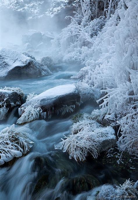 A Stream Running Through A Forest Filled With Snow Covered Rocks And