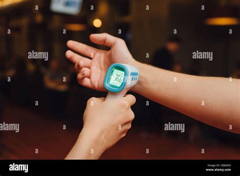 A Person Is Having Their Temperature Checked At Public Using A