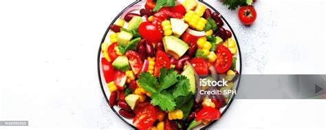 옥수수 팥 아보카도 할라 페노 토마토 양파 및 실란트로와 멕시코 매운 샐러드 하얀 돌 테이블 배경 상단보기 배너 강낭콩에 대한