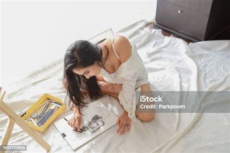 흰 셔츠를 입은 아시아 여성 예술가가 응접실에서 연필로 그림을 그린다 25 29세에 대한 스톡 사진 및 기타 이미지 Istock