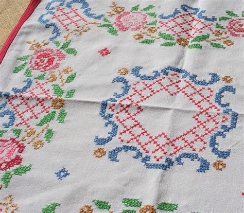 an embroidered tablecloth with flowers and leaves on it
