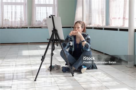 소녀 예술가 대리석 바닥에 앉아 기름 물감으로 페인트 흰색 캔버스와이 젤은 청록색과 밝은 녹색 벽과 함께 방에 대리석 타일의