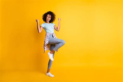 예쁜 운이 좋은 어두운 피부 물결 모양의 숙녀 입고 파란색 티셔츠 부상 주먹 고립 된 노란색 배경의 전체 길이 사진 T 셔츠에 대한 스톡 사진 및 기타 이미지 Istock