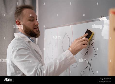 Teacher Cleaning The Whiteboard Holding Eraser Erasing In Classroom