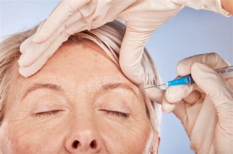보톡스 성형 수술 및 미용을 위한 얼굴 손 및 주사기 모형이 있는 회색 스튜디오 뒷면 성형 수술을 받은 노인 여성 콜라겐 리프팅