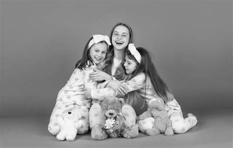Des Sœurs Heureuses Qui Sembrassent Assises Ensemble En Vêtements De Maison Avec Des Ours En