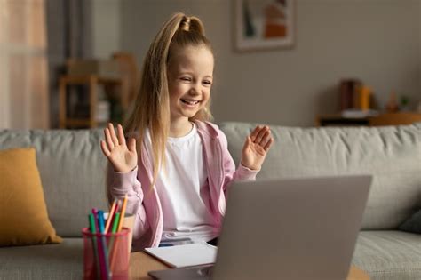Premium Photo Schoolgirl Making Video Call Waving Hello To Laptop At Home