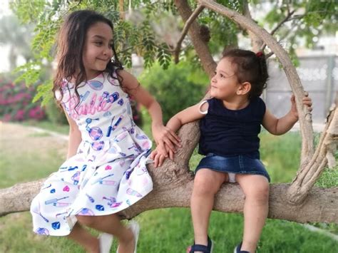 Premium Photo Cute Smiling Siblings Sitting On Tree In Park