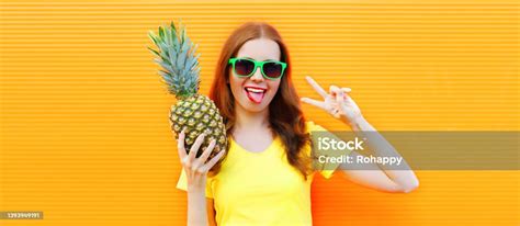 오렌지색 배경에 선글라스를 착용 한 파인애플을 가진 행복한 웃는 여성의 여름 초상화 20 29세에 대한 스톡 사진 및 기타